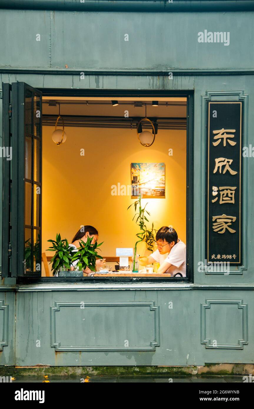 A couple dining seen through a window at Dongxin Restaurant on Wukang ...