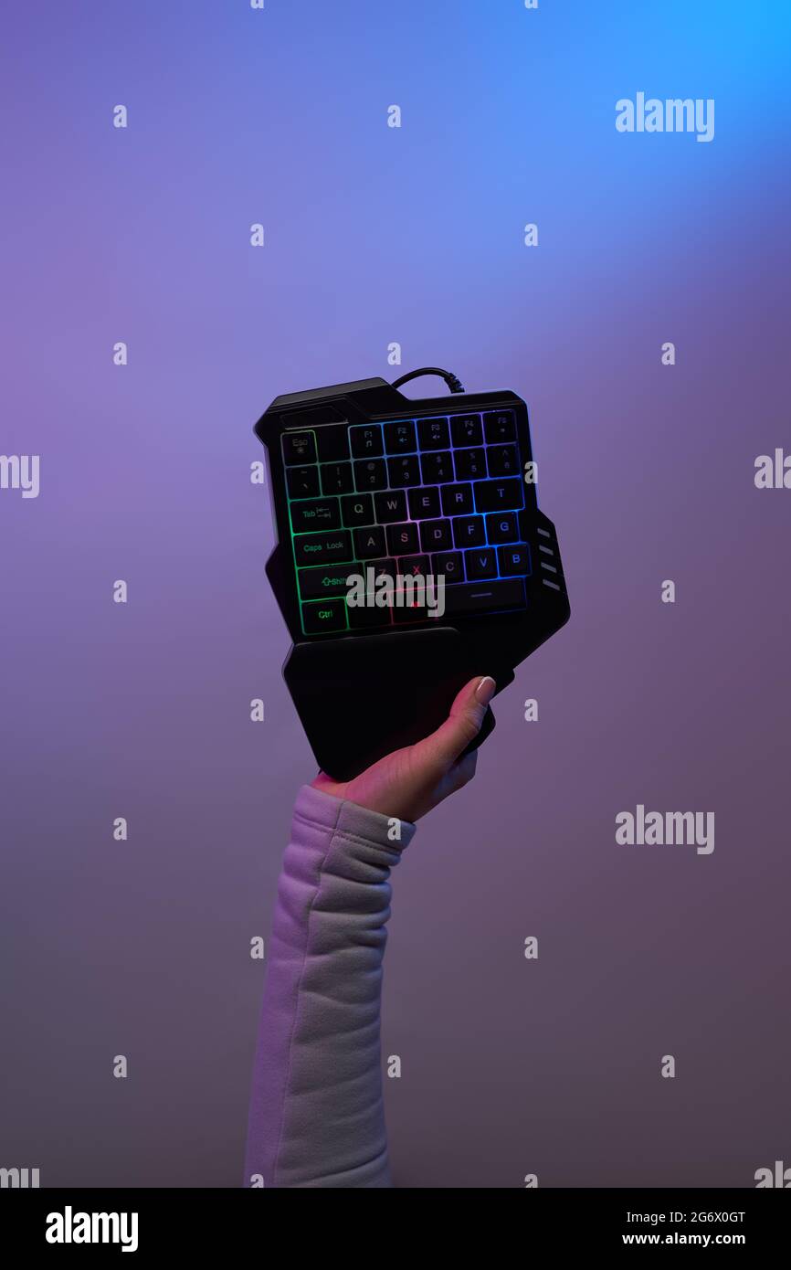 Hand with gamers keyboard on violet background. Gamer concept Stock ...