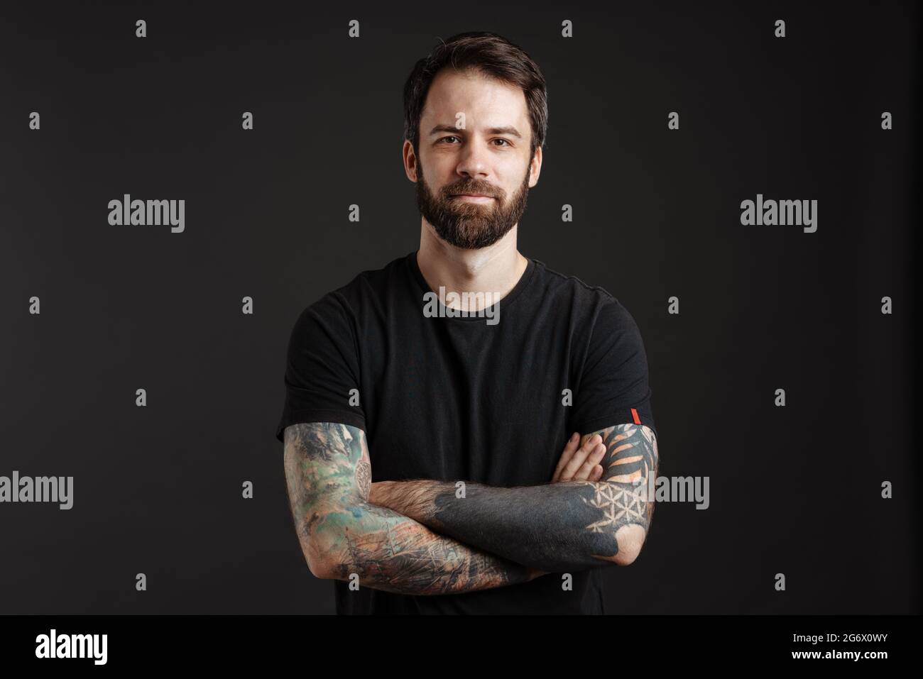 Bearded brunette man with tattoo posing and looking at camera isolated ...