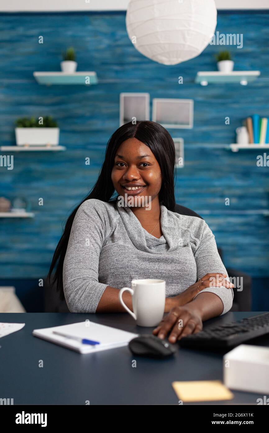 Portrait of african american student sitting at desk table in living ...