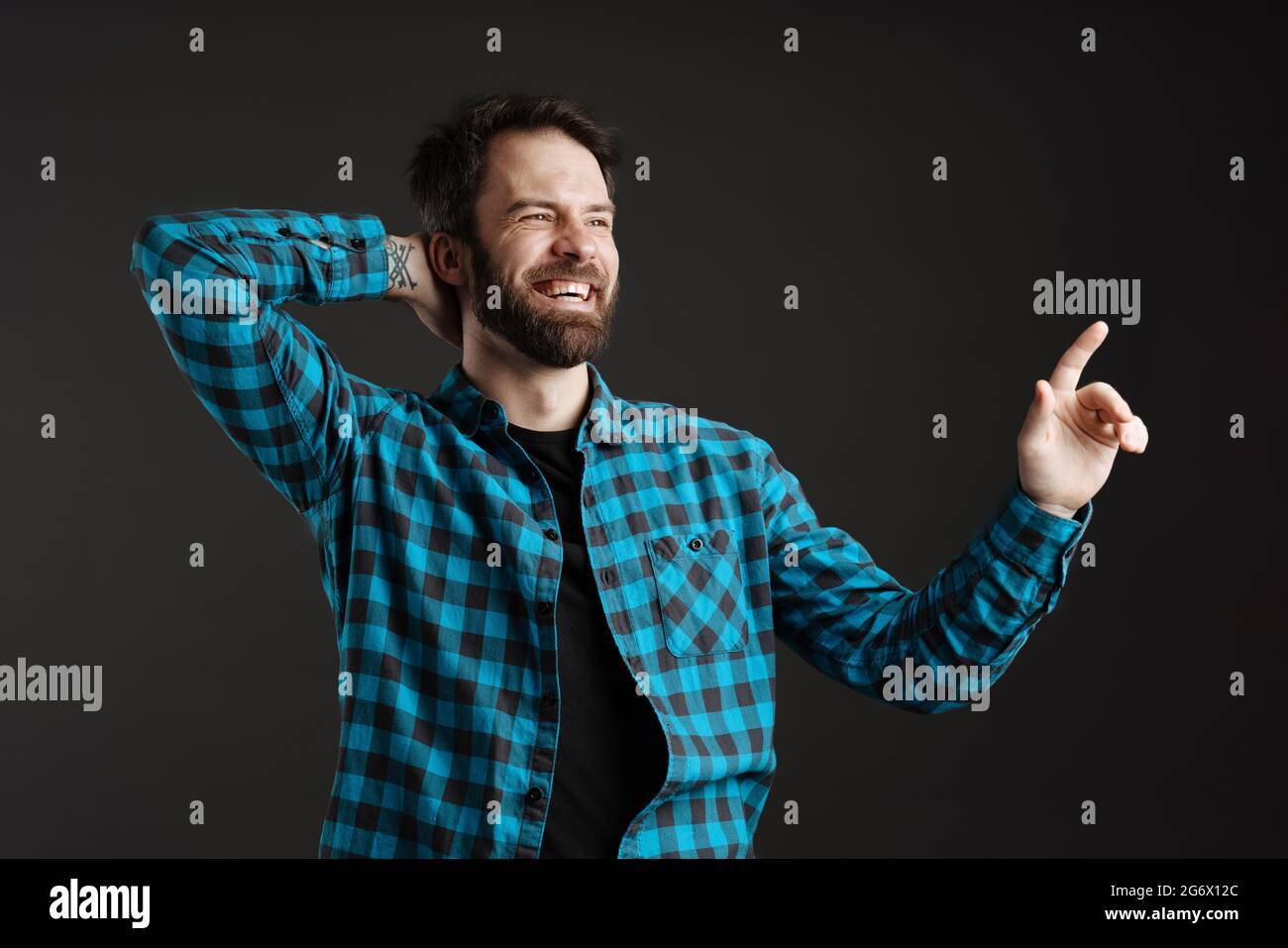Smiling bearded man pointing finger upward while holding his neck ...