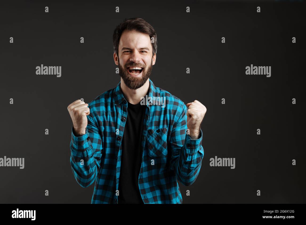 Bearded excite man in shirt laughing while making winner gesture ...