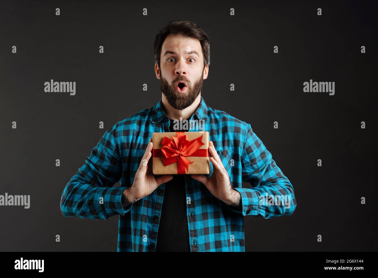 Bearded surprised white man exclaiming while showing gift box isolated ...