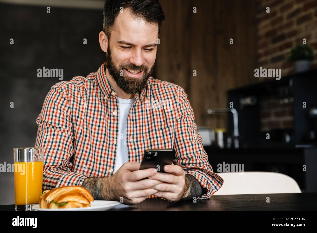 Smiling mid aged brunette man holding mobile phone, working with ...