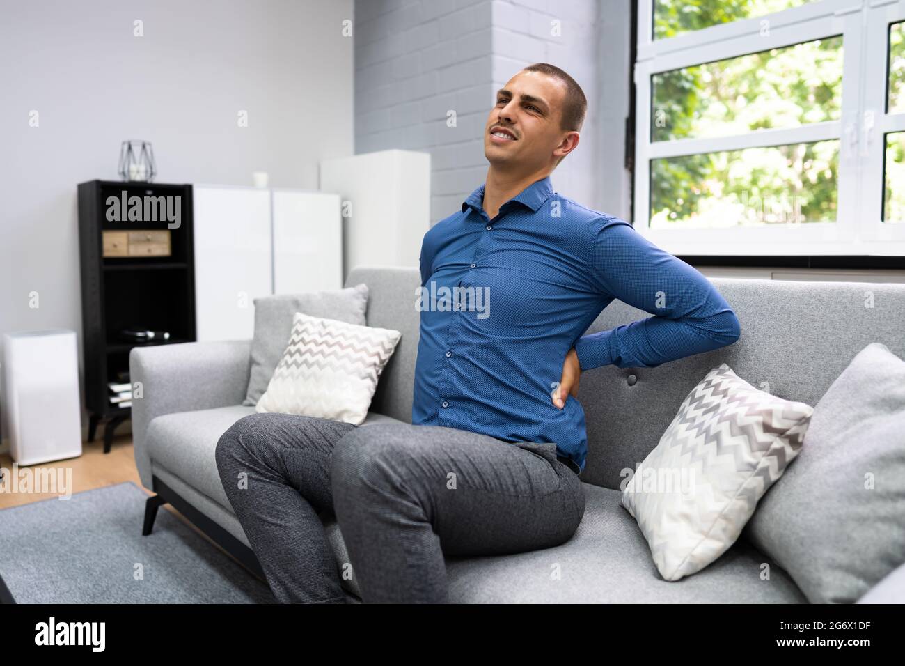 Man Sitting On Sofa Having Back Pain Stock Photo - Alamy