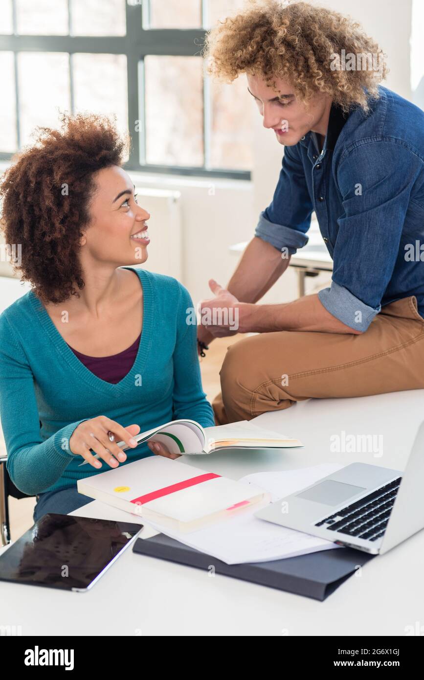 Two friendly classmates of different nationalities smiling while ...