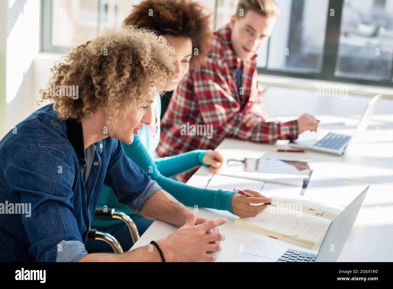 student in front of a book while sitting down at desk in the classroom ...