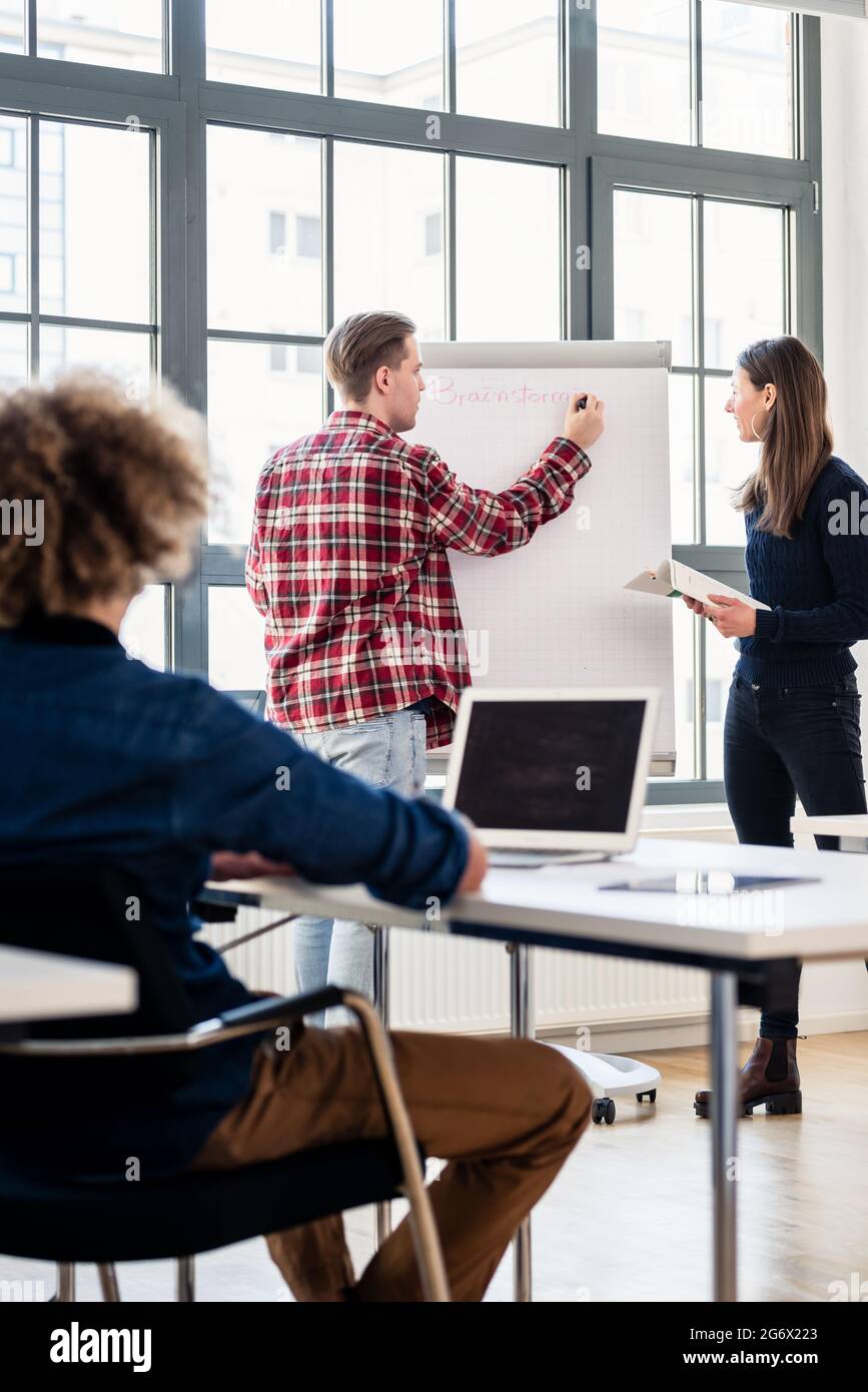 Rear view of a student writing on a training paper board while ...