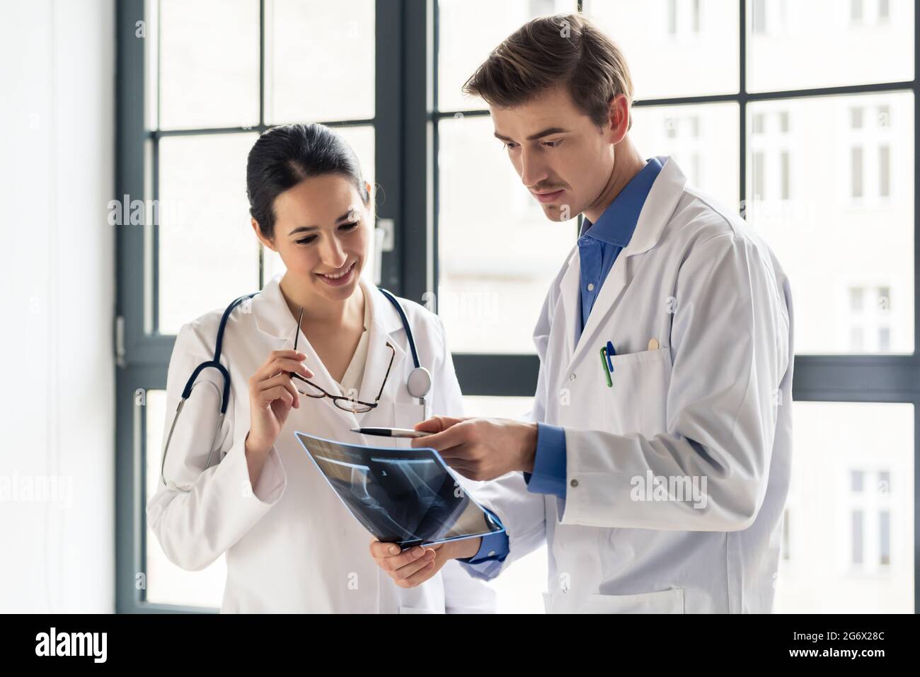 Two young dedicated doctors analyzing together the radiograph of the ...