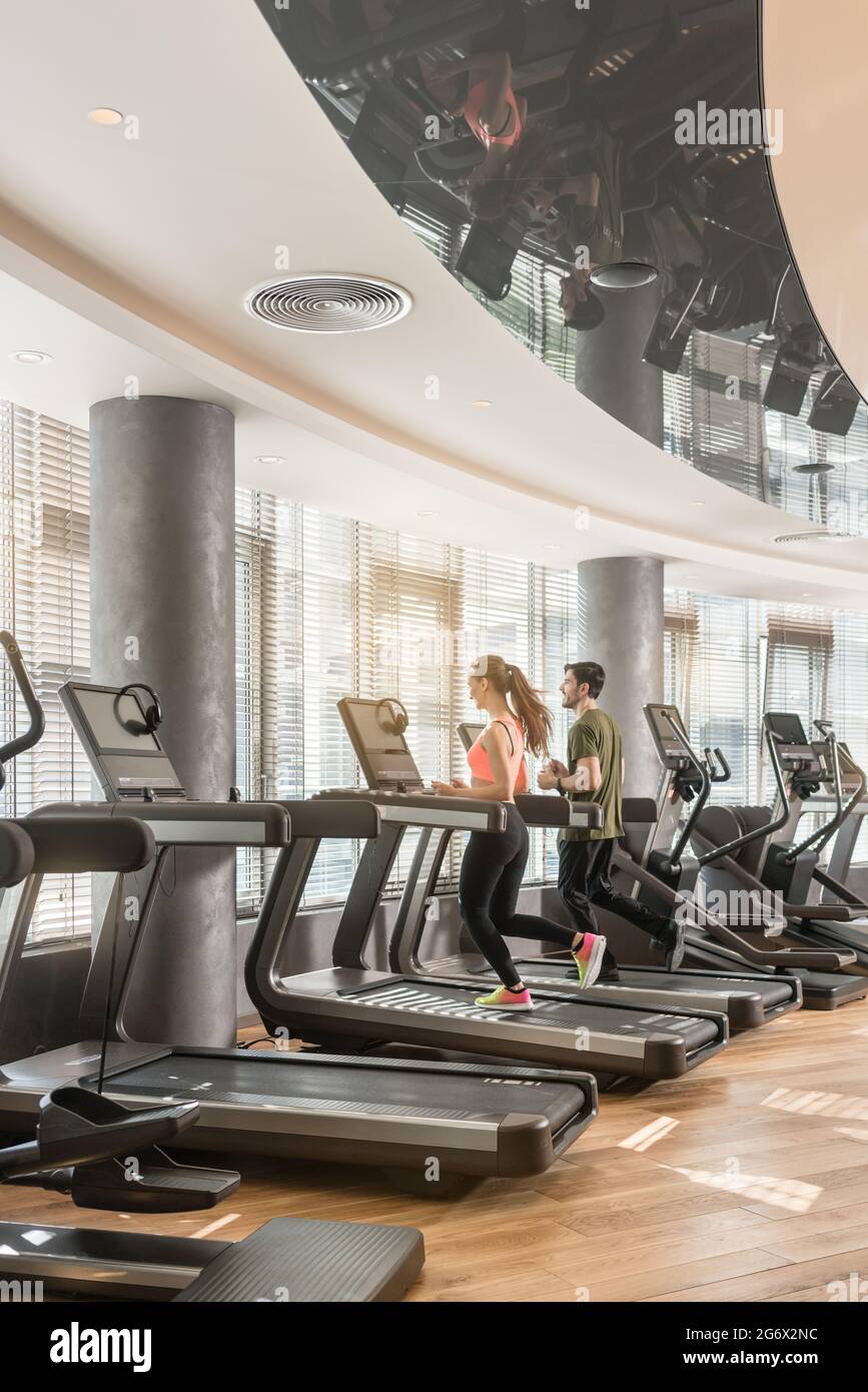 Side view of fit young man and woman smiling while running side by side ...