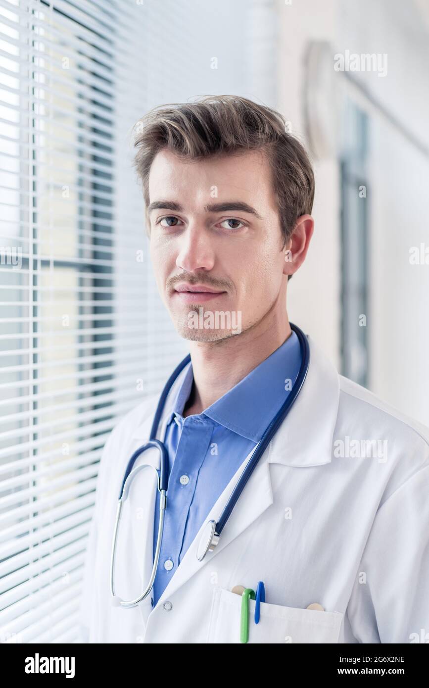 Close-up portrait of a young serious doctor looking at camera with ...