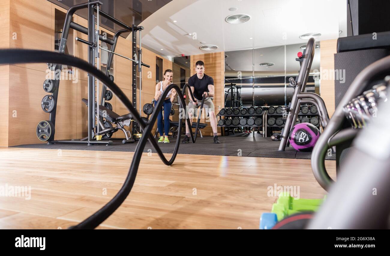 Low-angle view of a young determined man waving battle ropes with ...