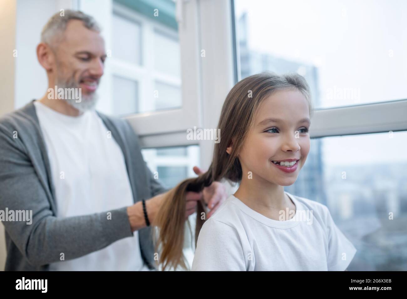 A gray-haired dad doing hair to his daughter Stock Photo - Alamy