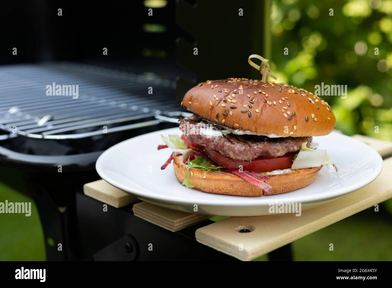 Homemade tasty cheeseburger being cooked on a on backyard barbecue ...