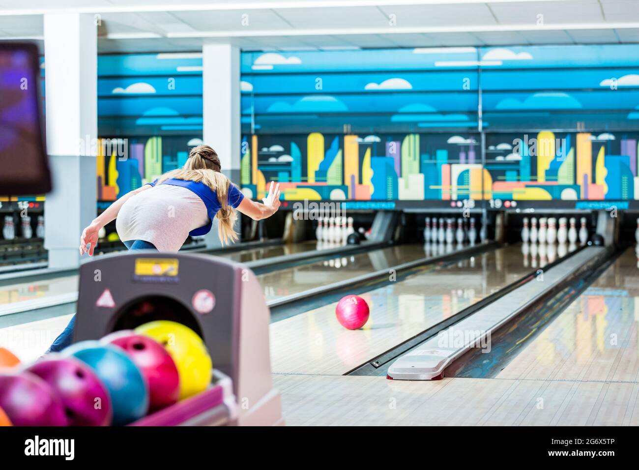 Rear view of a young woman throwing bowling ball Stock Photo - Alamy