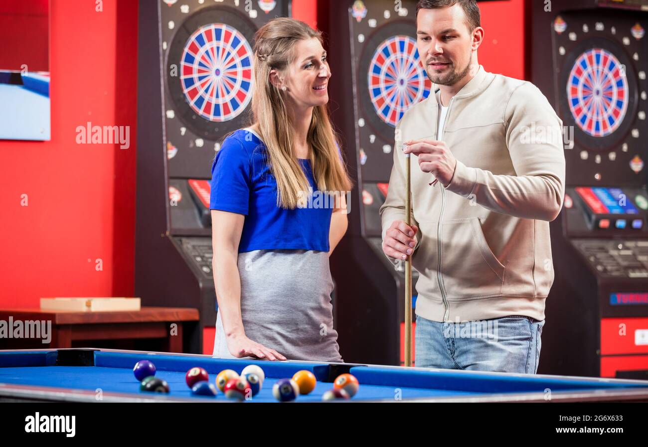 Happy wife looking at husband while playing billiard in club Stock ...