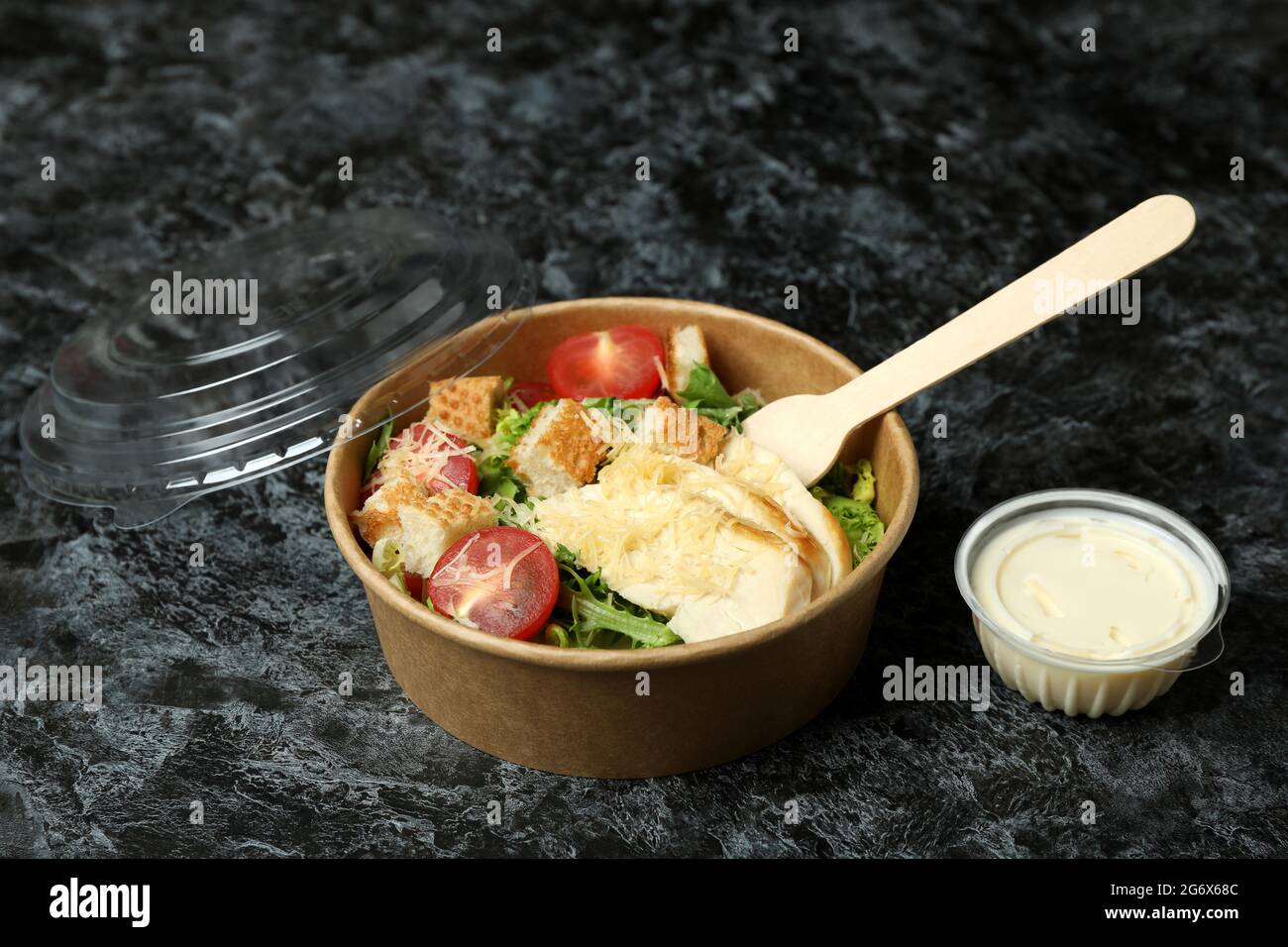 Concept of tasty eating with Caesar salad on black smokey background ...