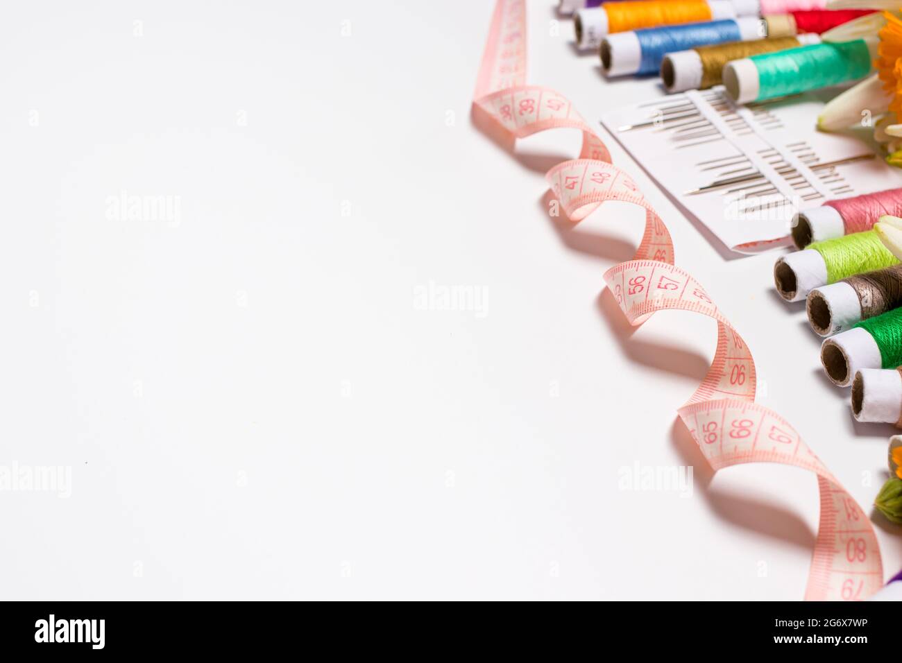 Tape measure, threads and needles on white with space for the text of ...