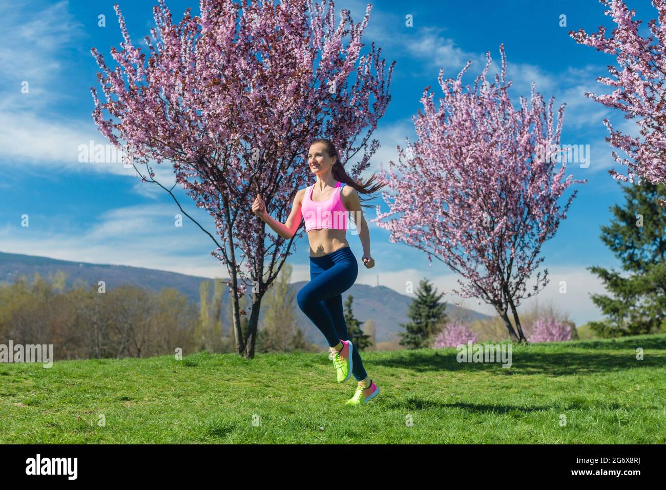 Woman doing sport running on hill between cherry trees blossoming Stock ...