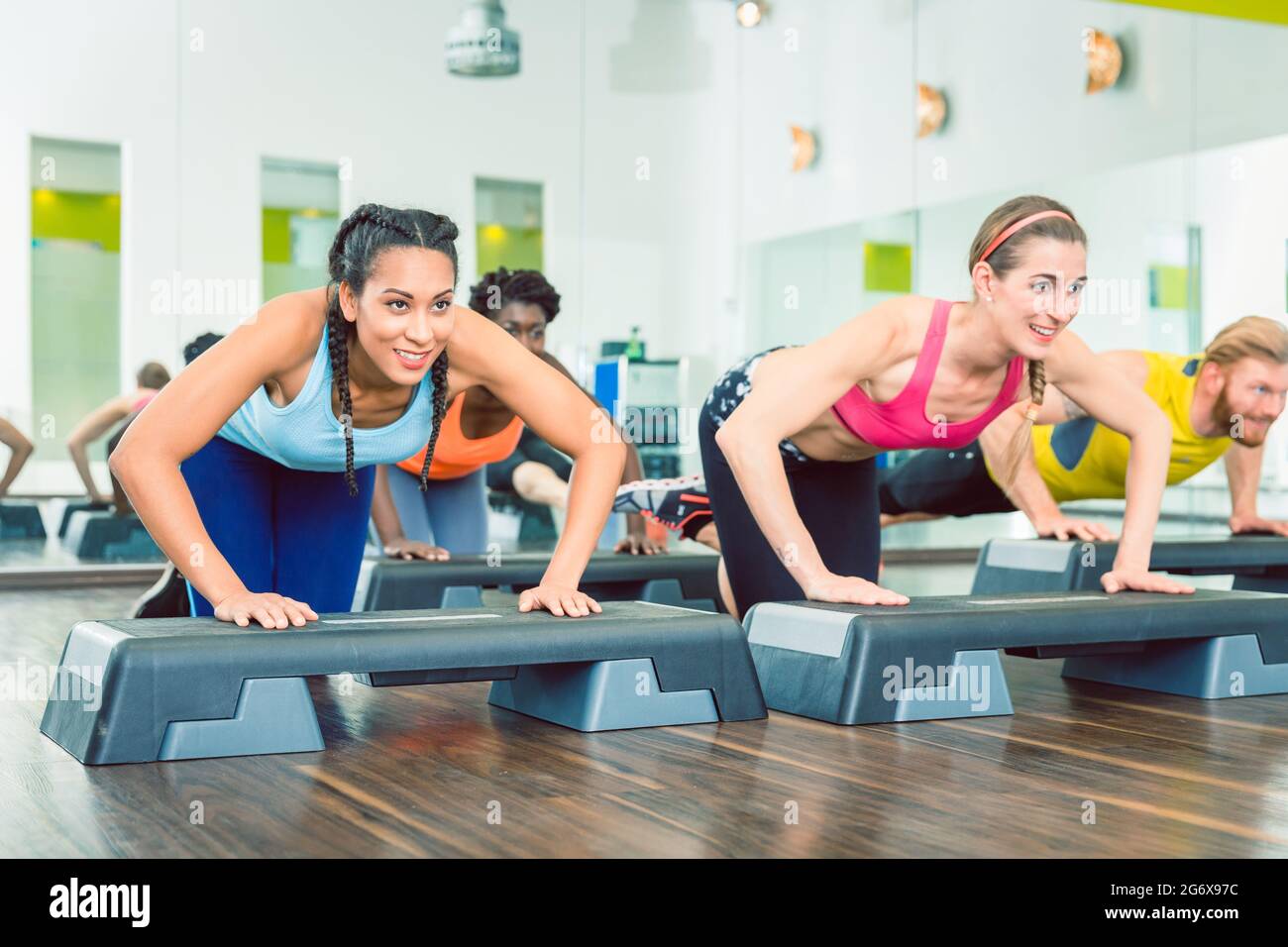 Determined young women exercising push-ups on aerobic stepper platforms ...