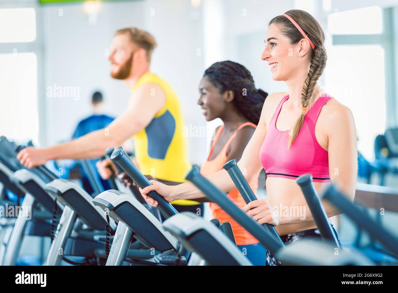 Side view of a fit happy woman and her training group on treadmill in ...