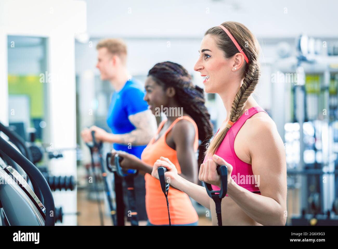 Side view of a fit happy woman wearing pink fitness bra while cycling ...