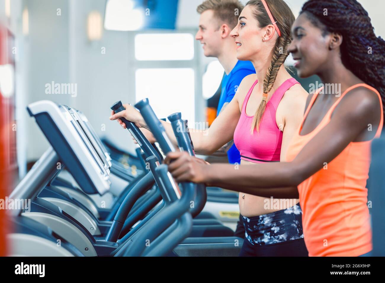 Side view of a fit happy woman and her training group on treadmill in ...