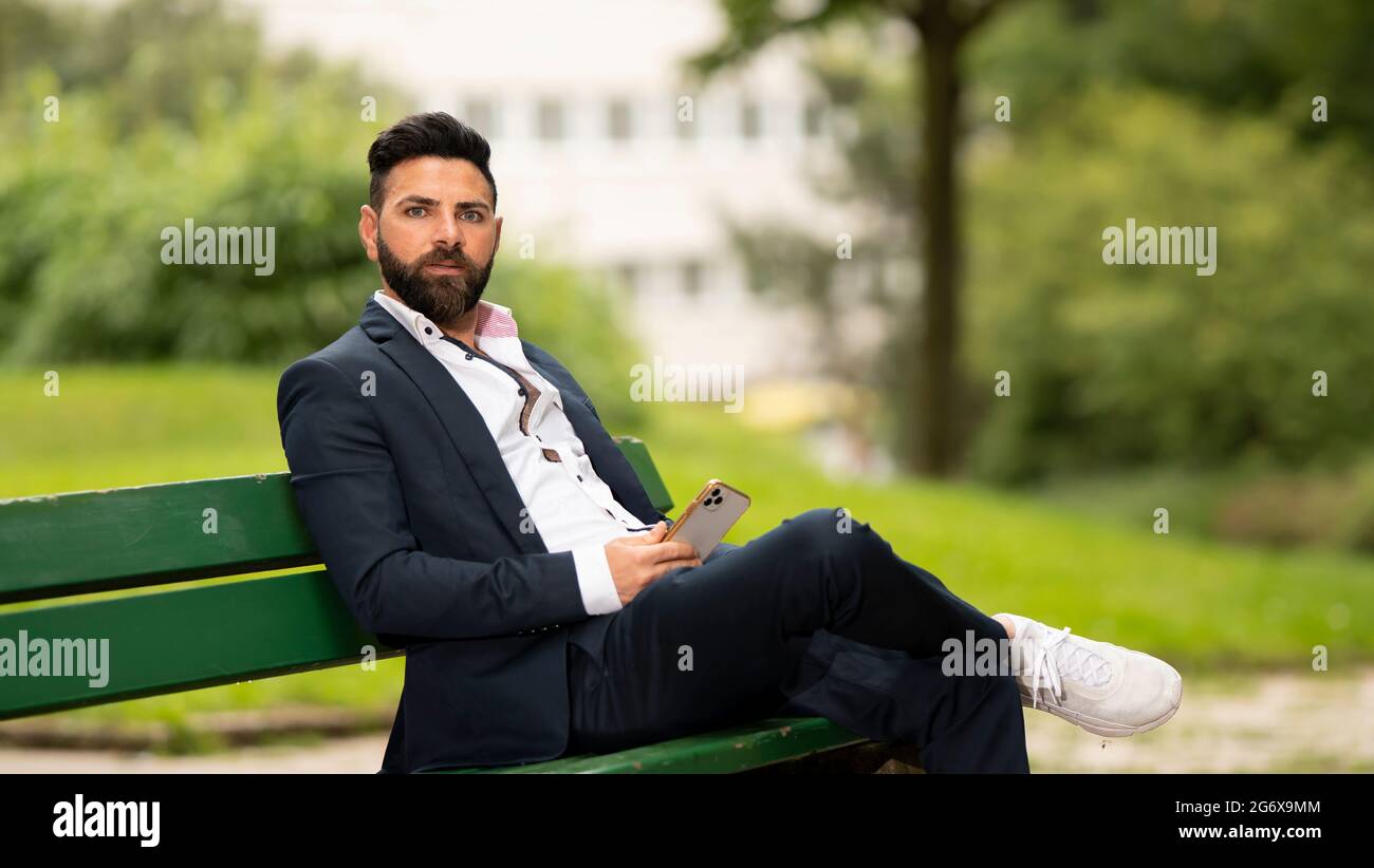 A handsome young man sit Handsome guy sitting on a park bench Young ...
