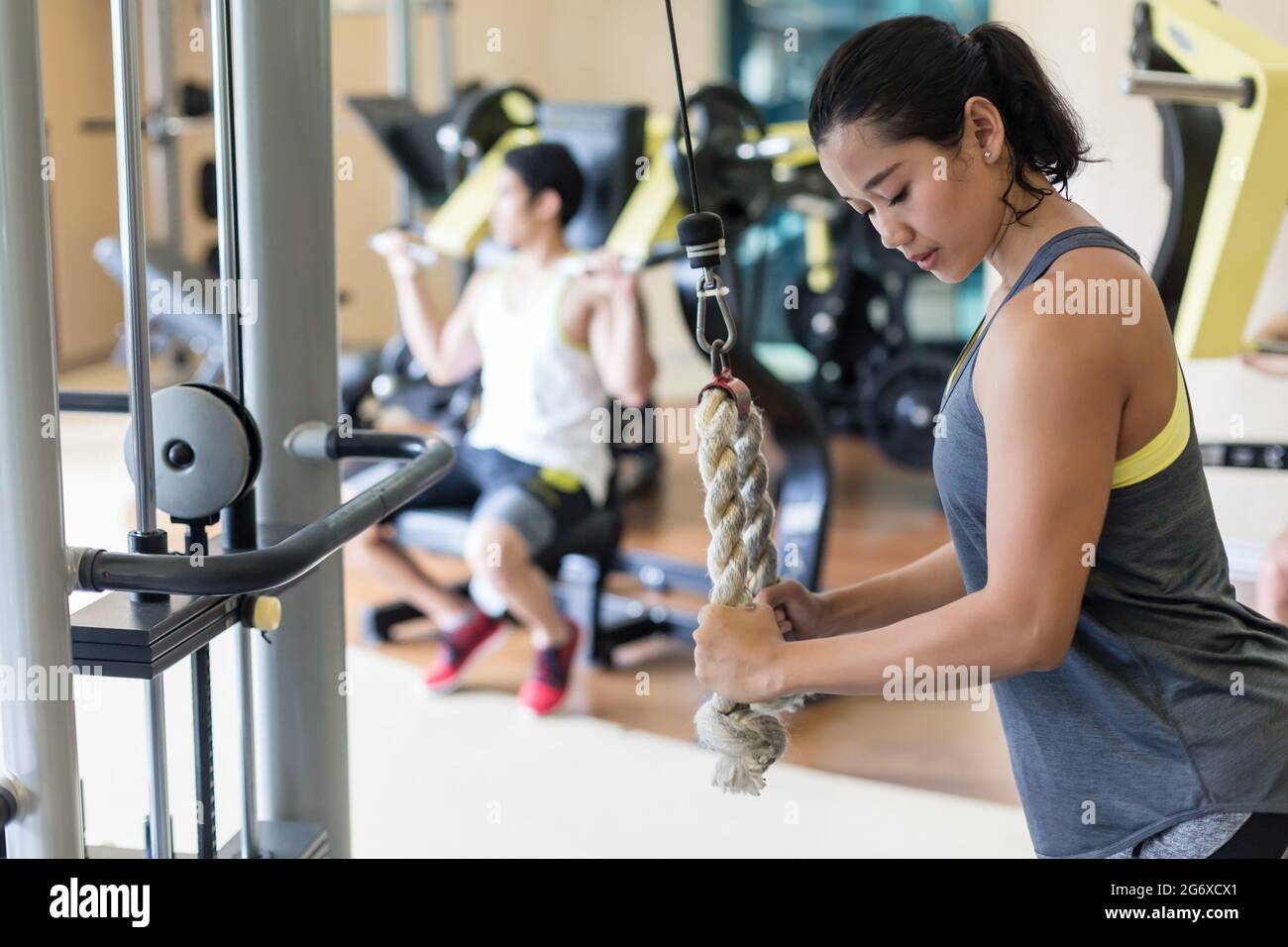 Side view of a determined young woman exercising cable rope triceps ...
