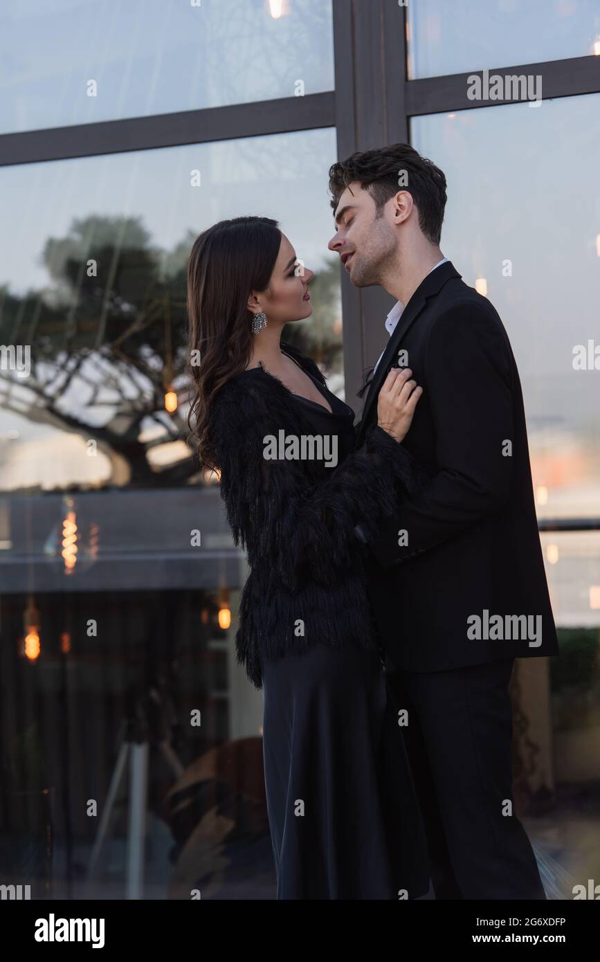 side view of happy woman in faux fur jacket hugging man in suit Stock ...
