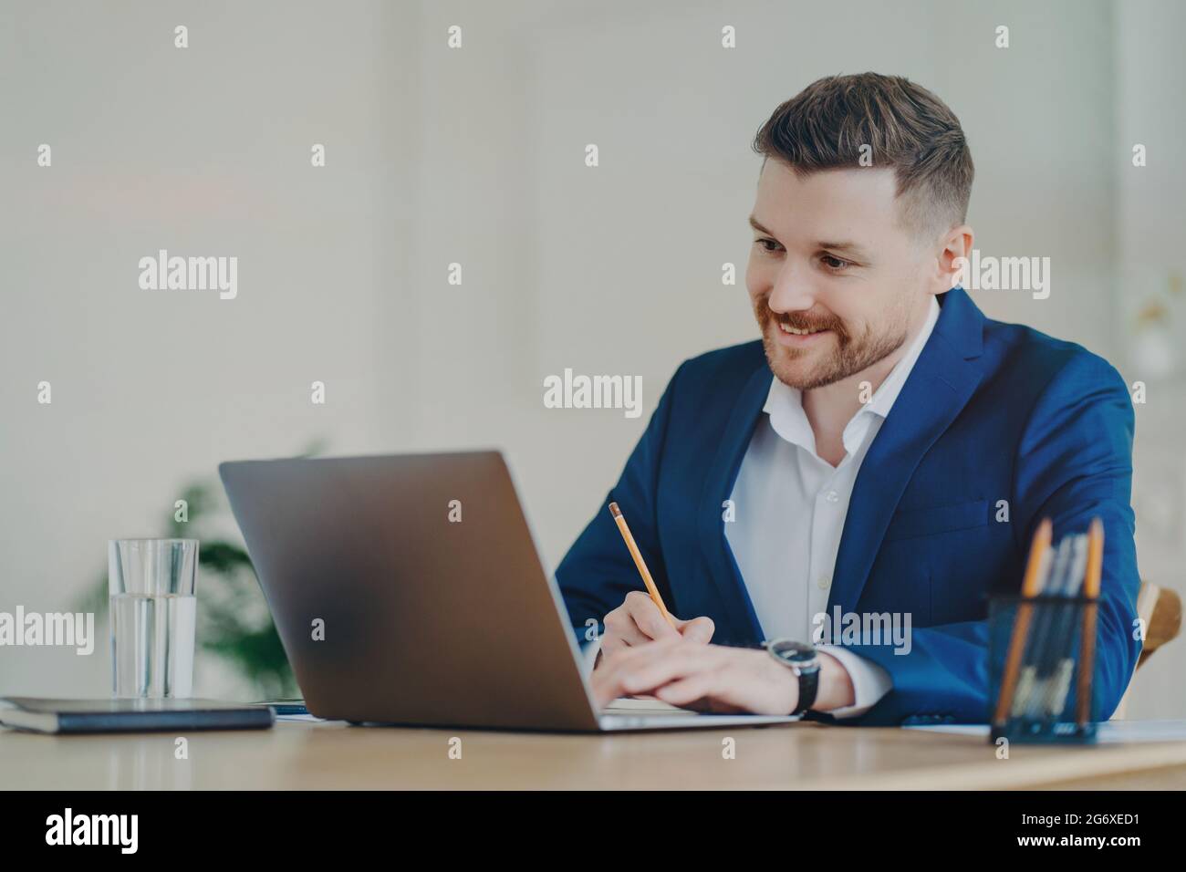 Corporate worker in formal suit sits at desktop focused at laptop ...