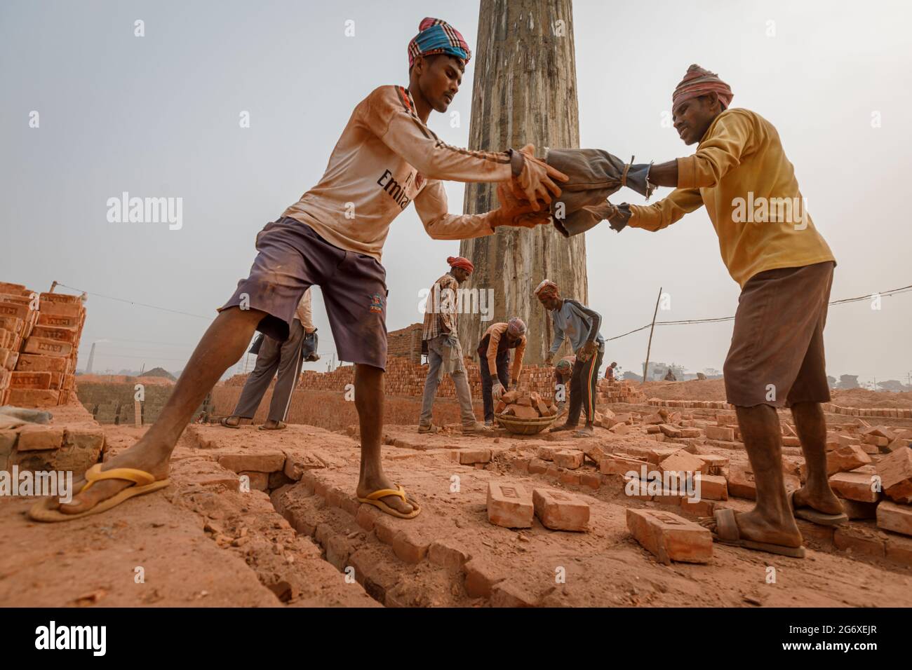 Workers stacking freshly "baked" bricks at a brick kiln in Ashulia ...
