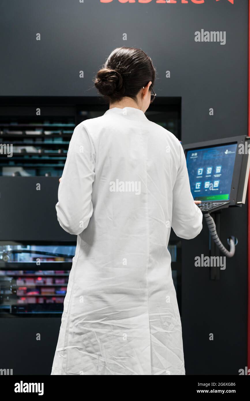 Low-angle rear view of an experienced female pharmacist using a ...