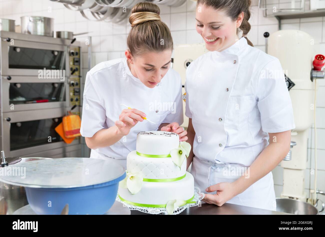 Two pastry bakers decorating large cake in bakery workshop Stock Photo ...