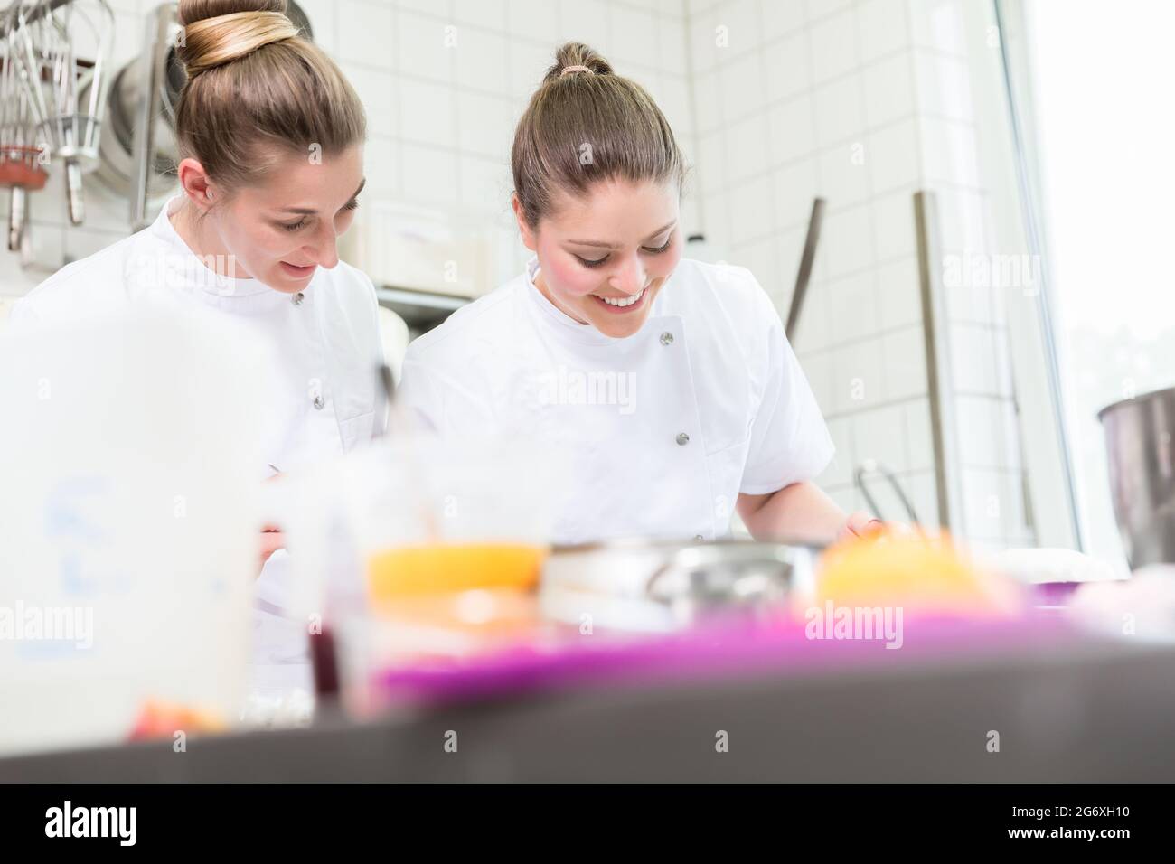 Women in fine bakery or pastry shop baking cakes helping each other ...