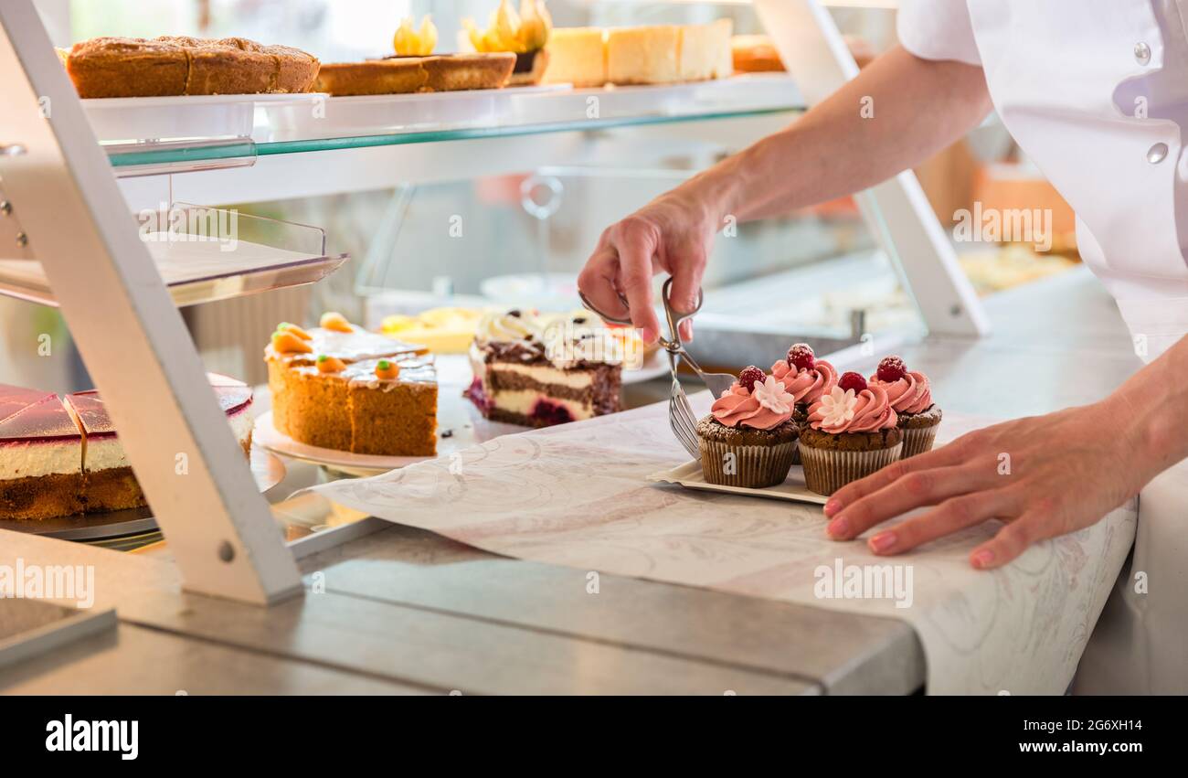 Baker sales woman putting various pies and cakes on display Stock Photo ...