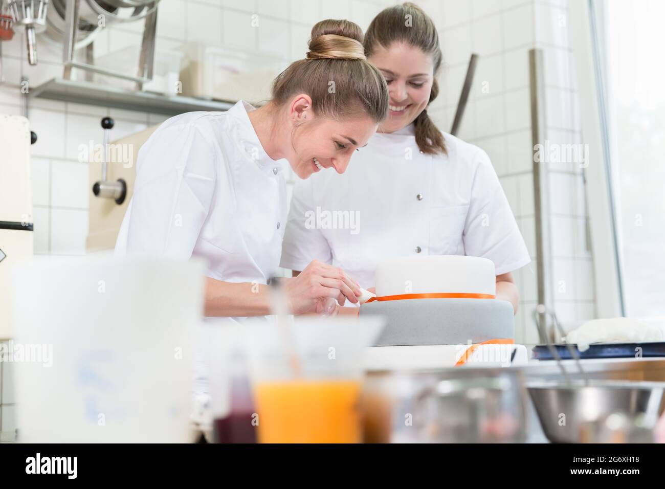 Women in fine bakery or pastry shop baking cakes helping each other ...