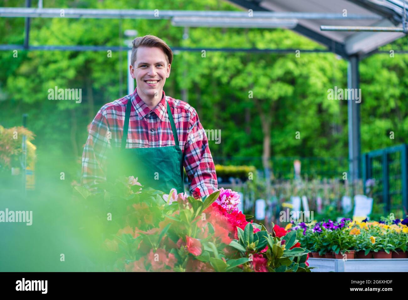 Handsome young man smiling happy while working as florist in a modern ...