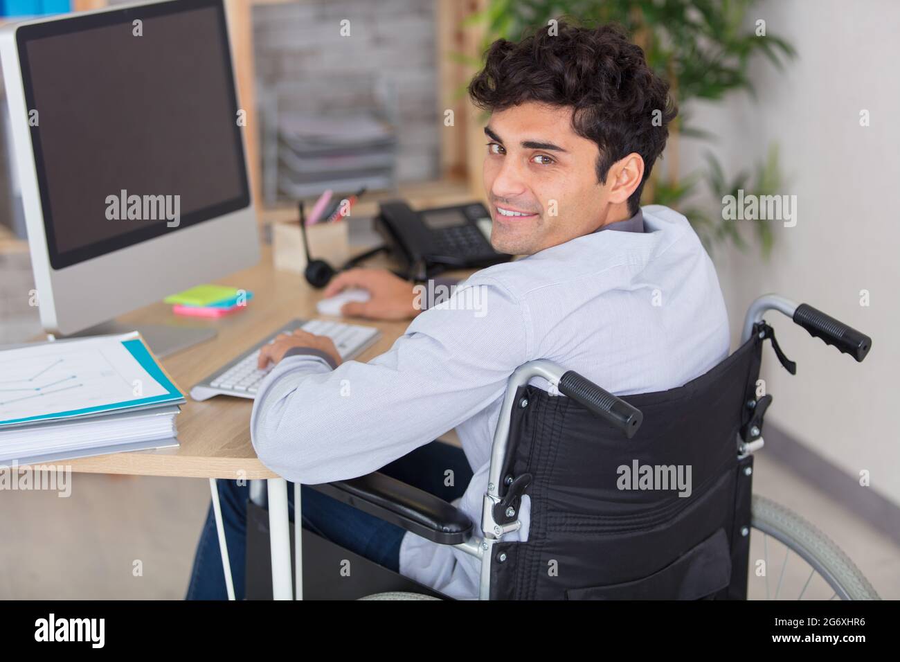 disabled man sitting at desk in wheelchair Stock Photo - Alamy