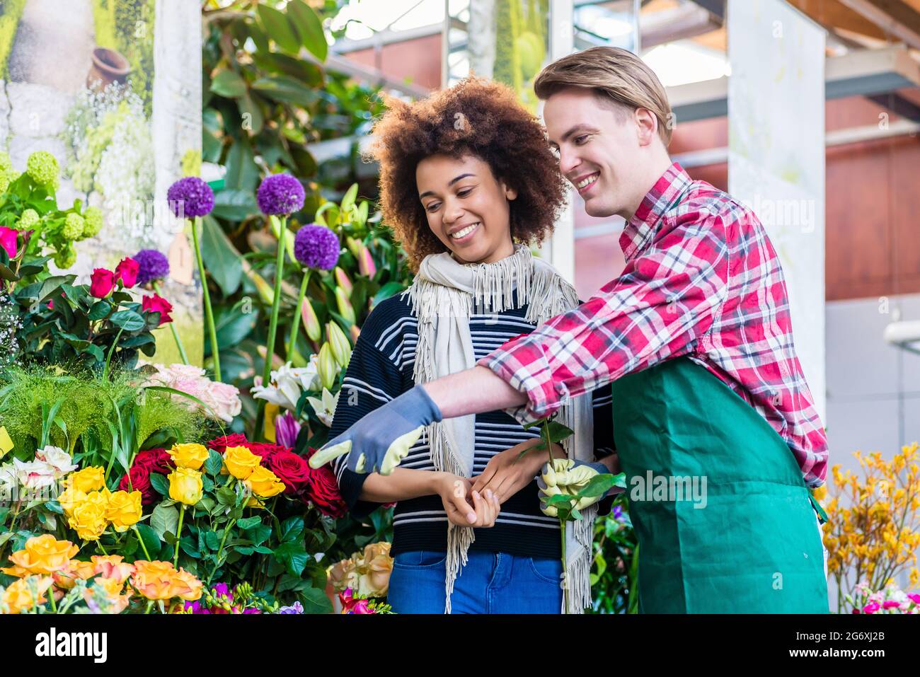 Beautiful Latin American woman buying freesias at the advice of a helpful and handsome vendor in ...