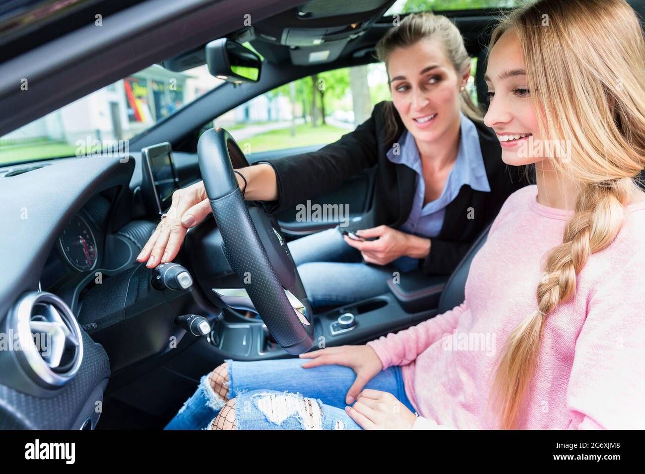 Student on wheel of car in driving lesson with her teacher learning to ...