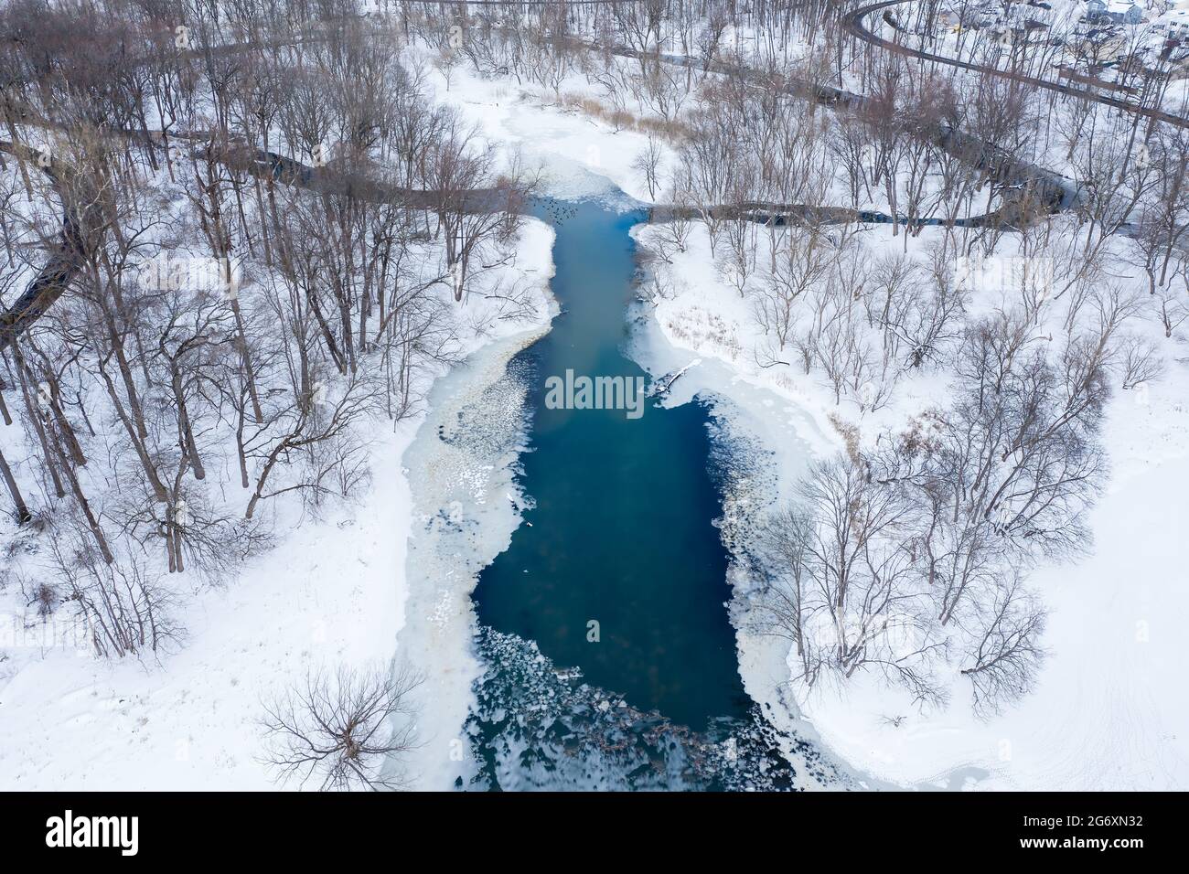 Aerial of a river with snow and ice surrounding it and bare trees Stock ...