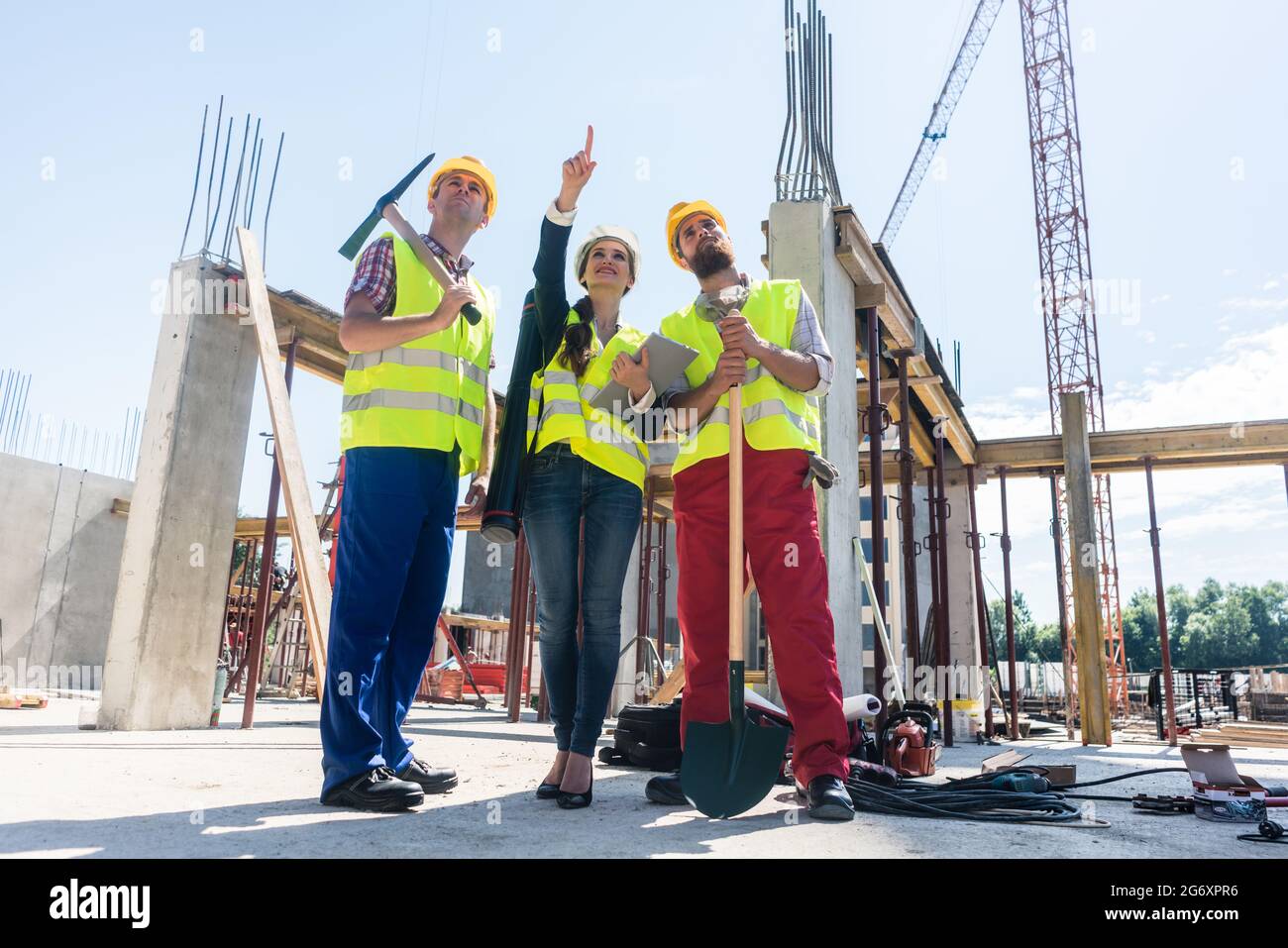 Low-angle view of a visionary architect pointing up while guiding and ...