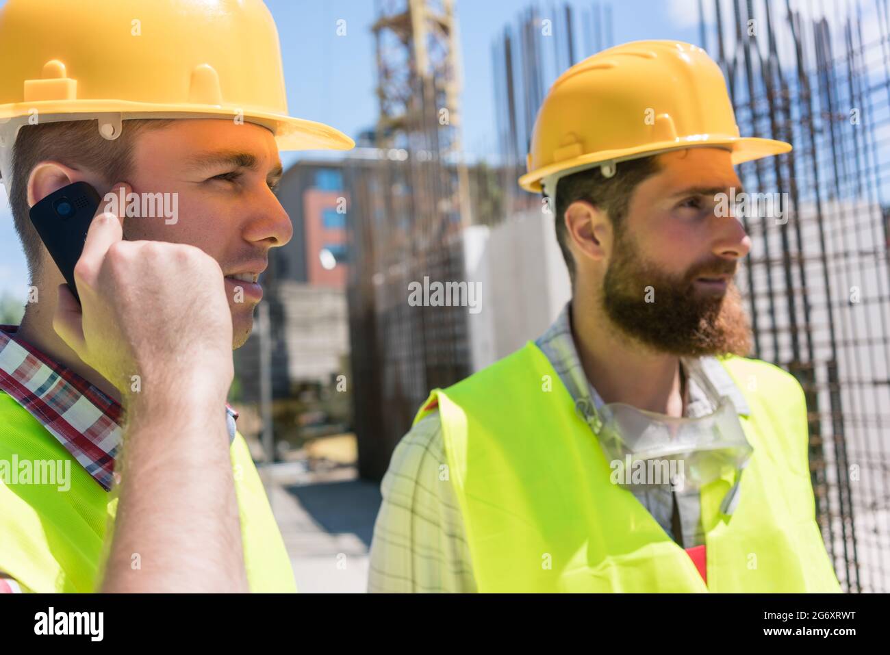 Side view close-up of a worker wearing yellow hard hat, while talking ...