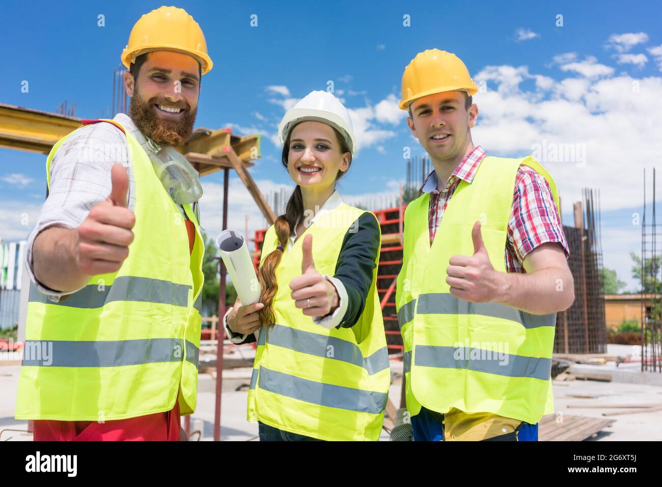 Portrait of three cheerful colleagues in a construction team looking at ...