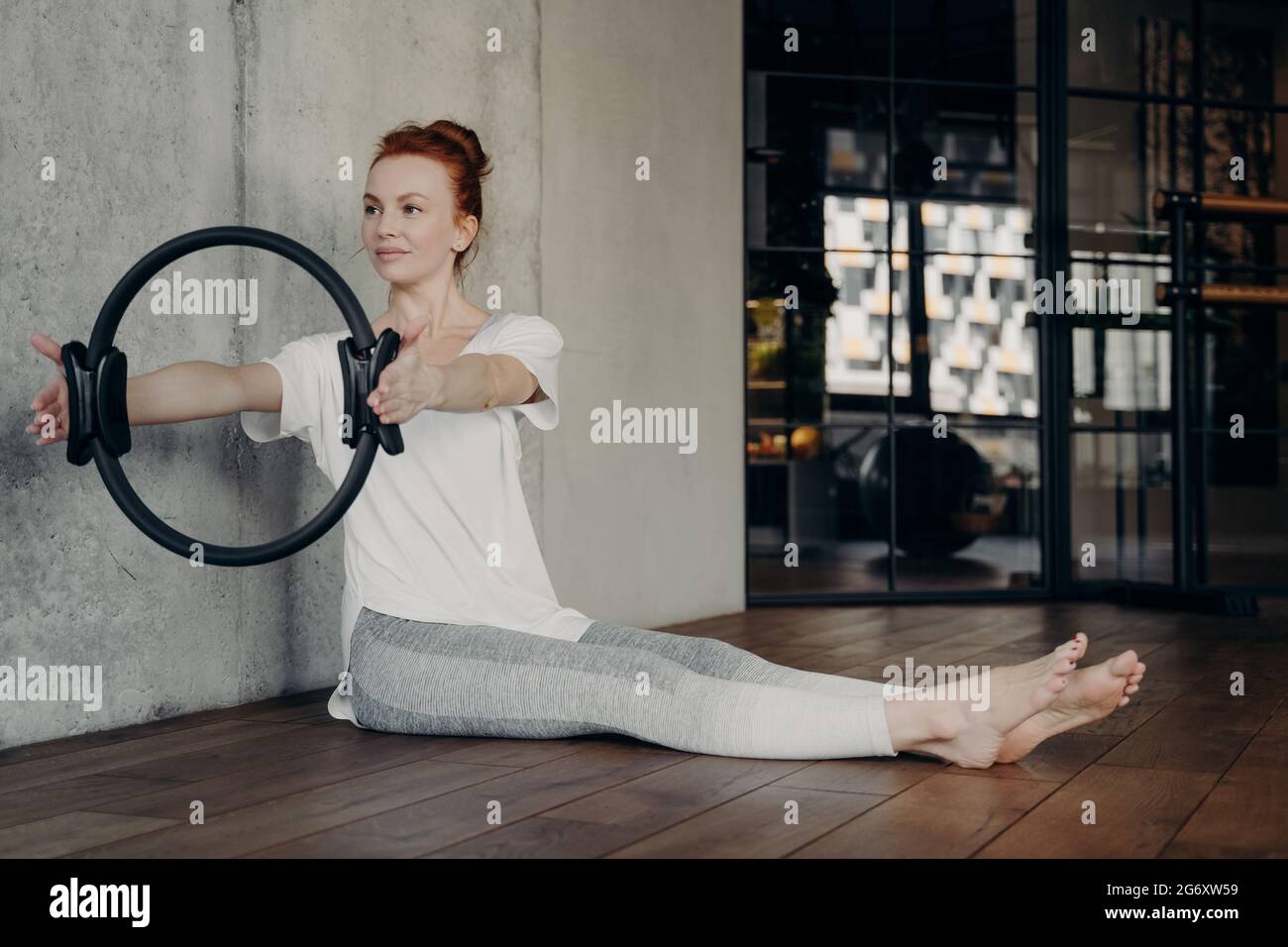 Young Focused Redhead Woman Doing Strength Exercises With Pilates Ring