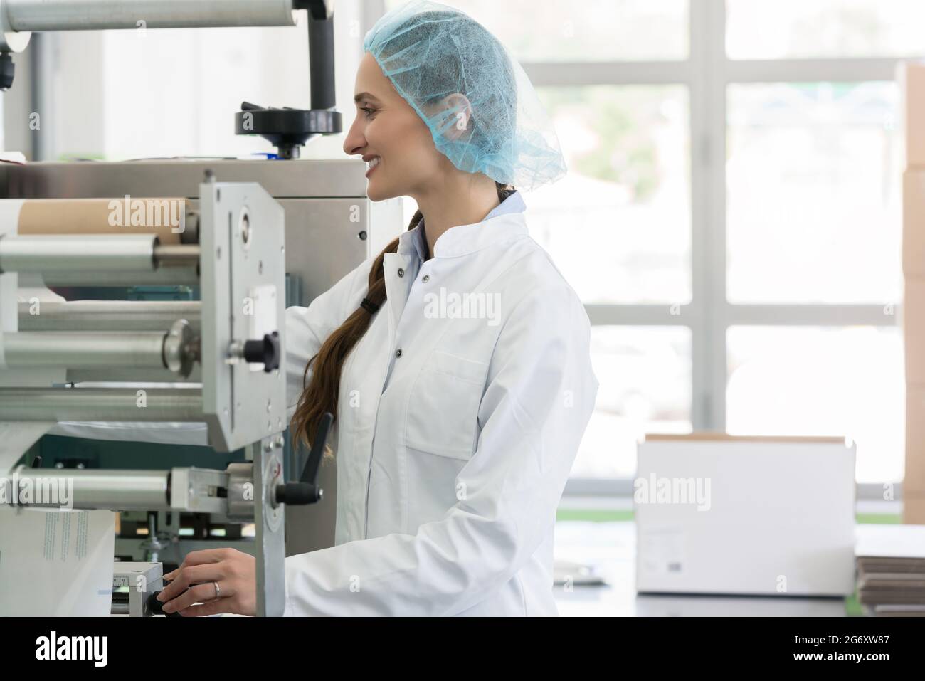 Happy female manufacturing operator wearing white lab coat and ...