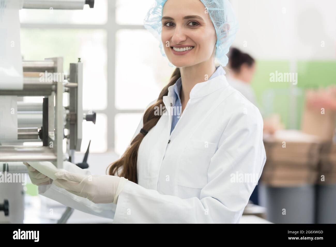 Side view of a happy manufacturing employee wearing white lab coat ...