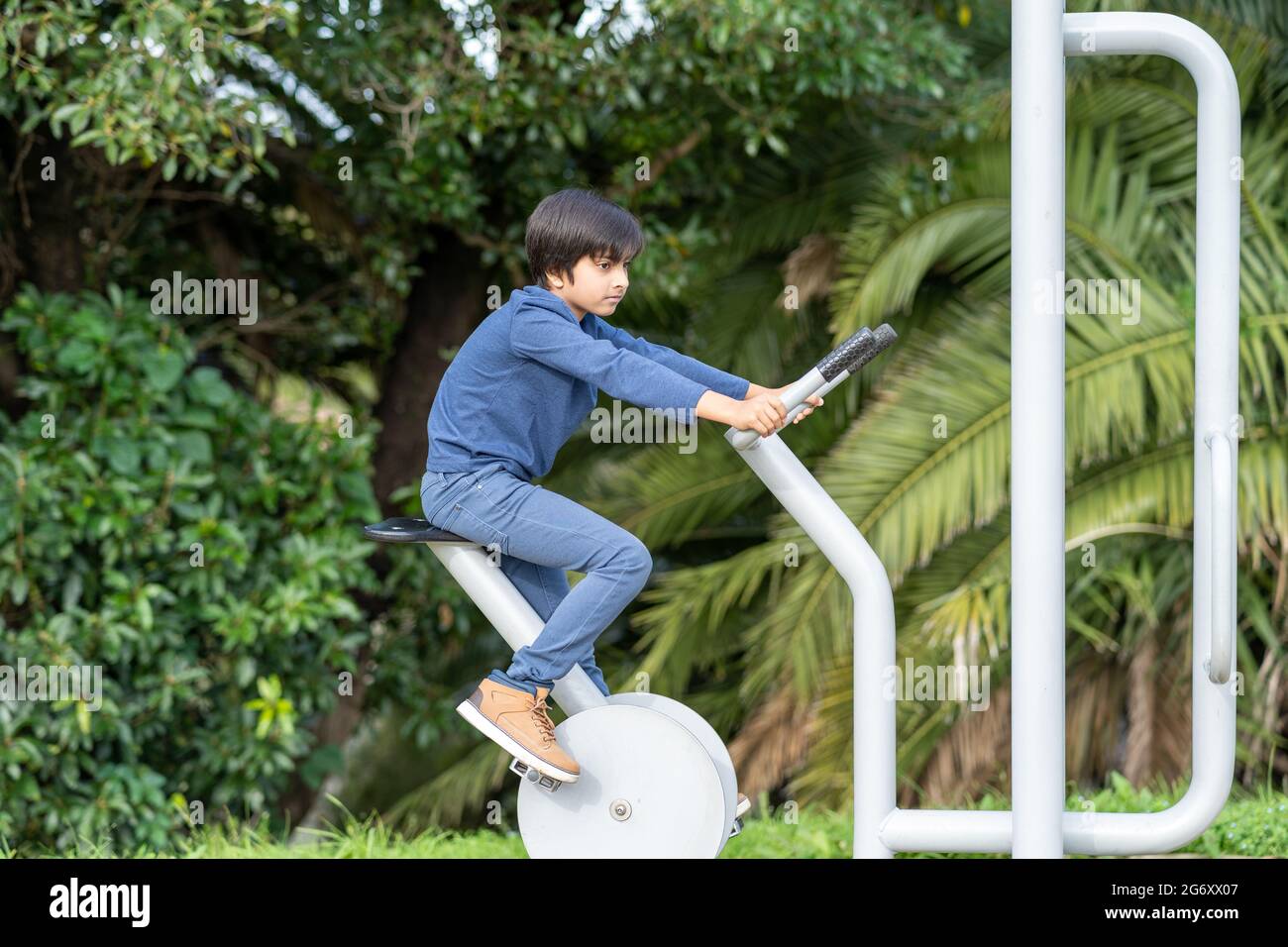 Young healthy boy doing exercise on gym machine. Kid on training bike ...