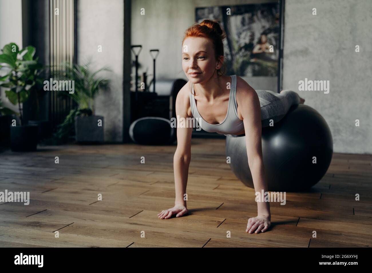 Fit woman balancing on exercise ball in fitness studio during pilates ...